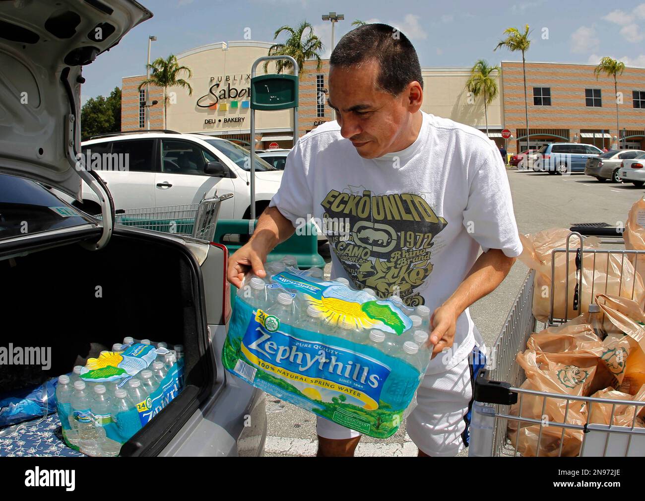 Carlos Eduardo Perez loads water into the trunk of his car as he ...