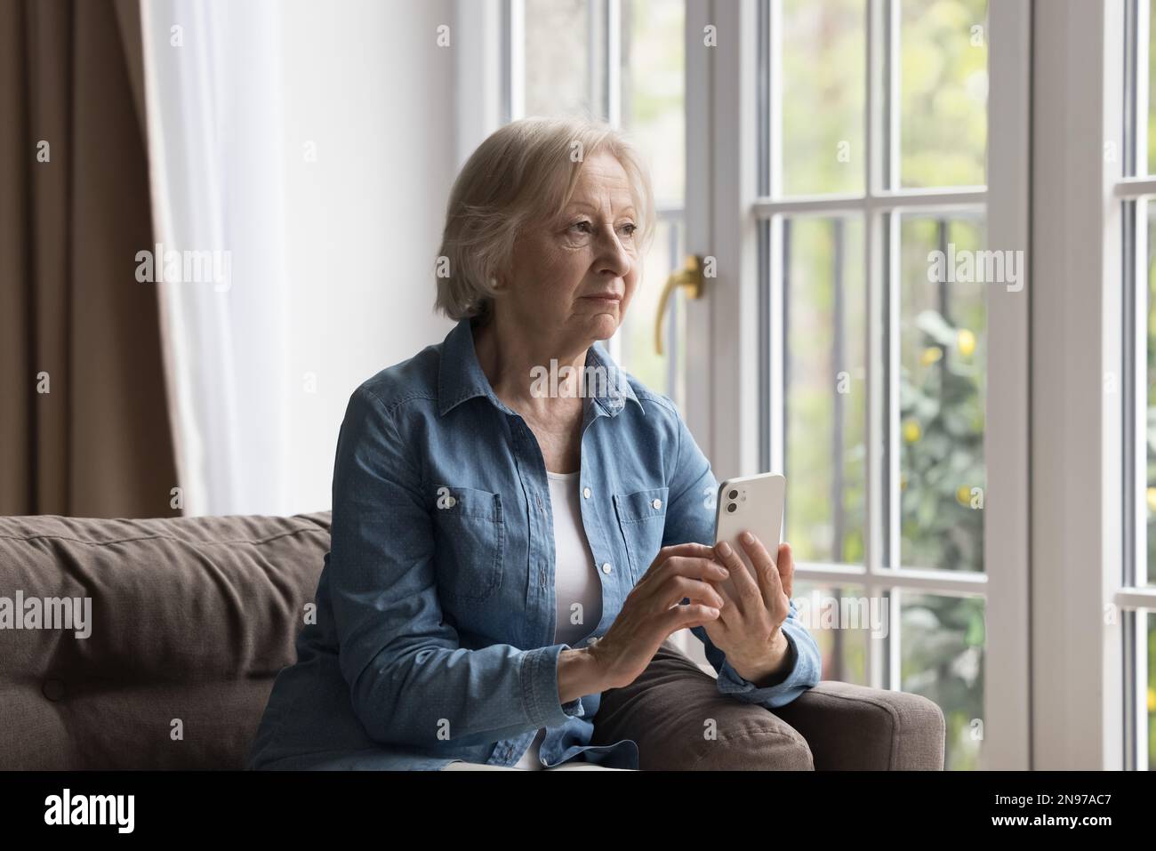Serious pensive lady using mobile phone for communication Stock Photo ...