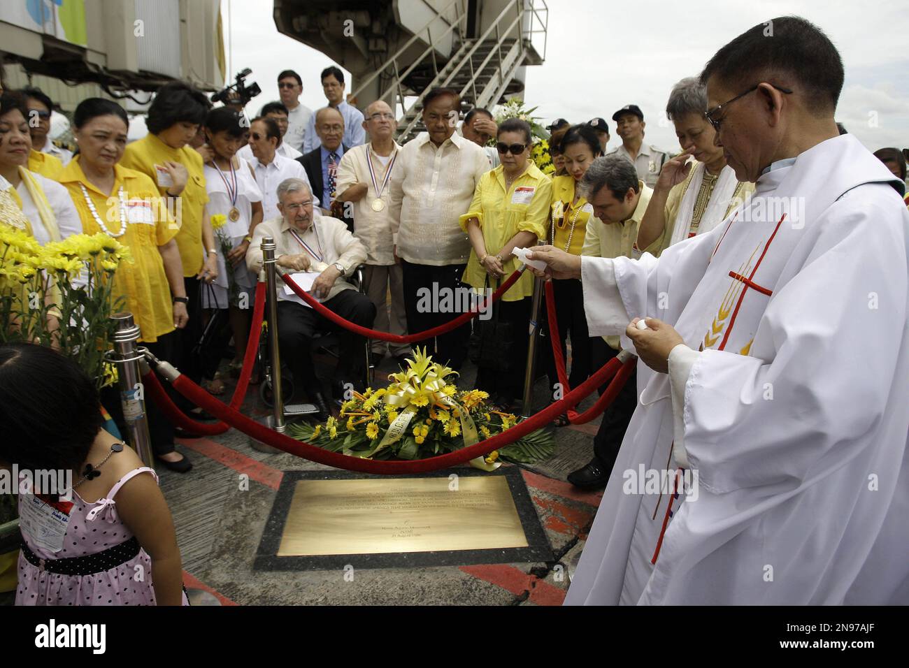 A priest sprinkles holy water at the marker of the late senator Benigno ...