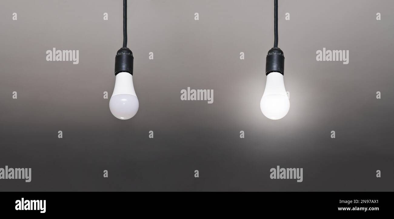 two lamps, one is lit, the other is not. a concept good idea. on a gray ...