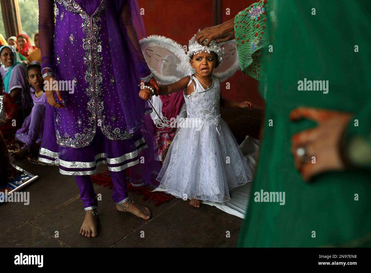 An Indian Muslim girl dressed as a fairy reacts as she waits for Eid al ...