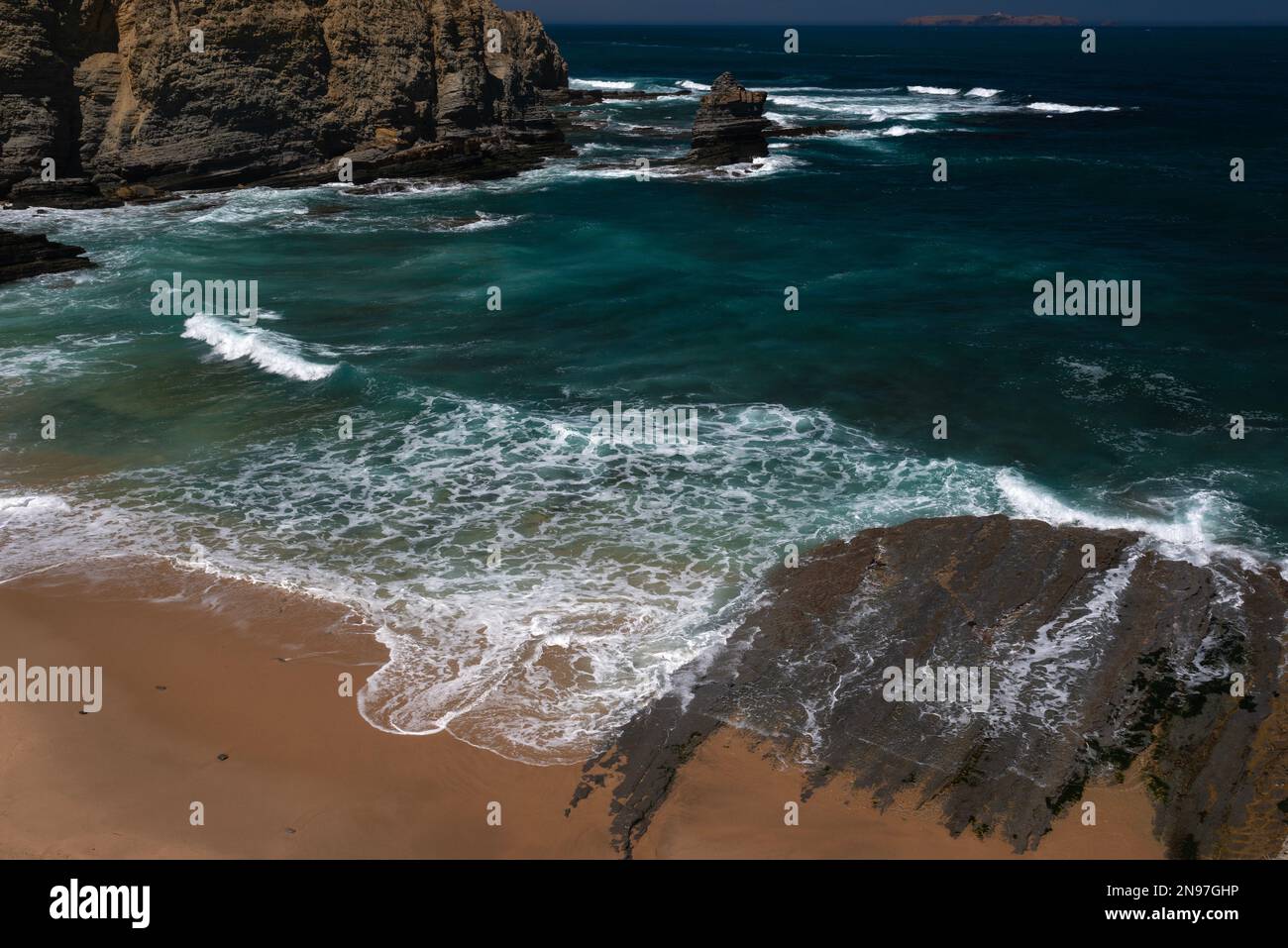Atlantic foam advances up a sloping sandy beach and across a flat ...