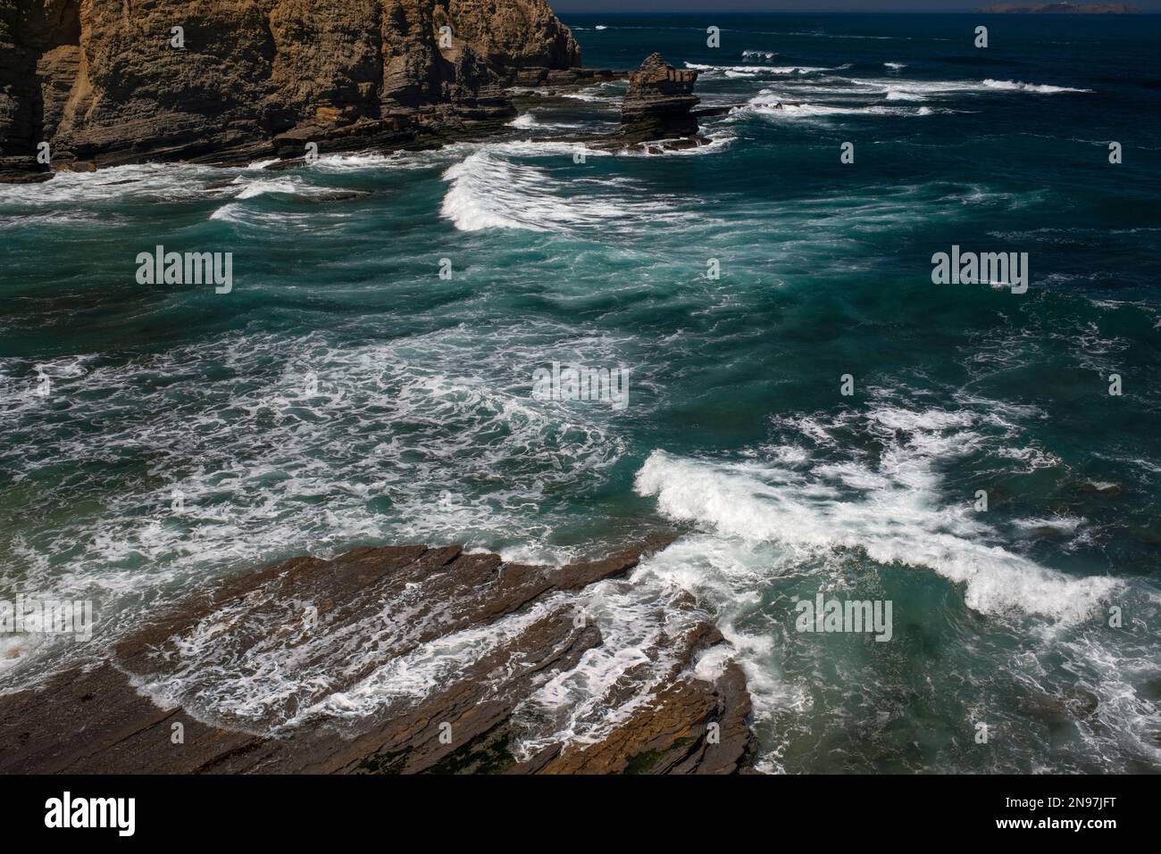 Foaming Atlantic surf swirls around a stack rock or sea pillar below ...