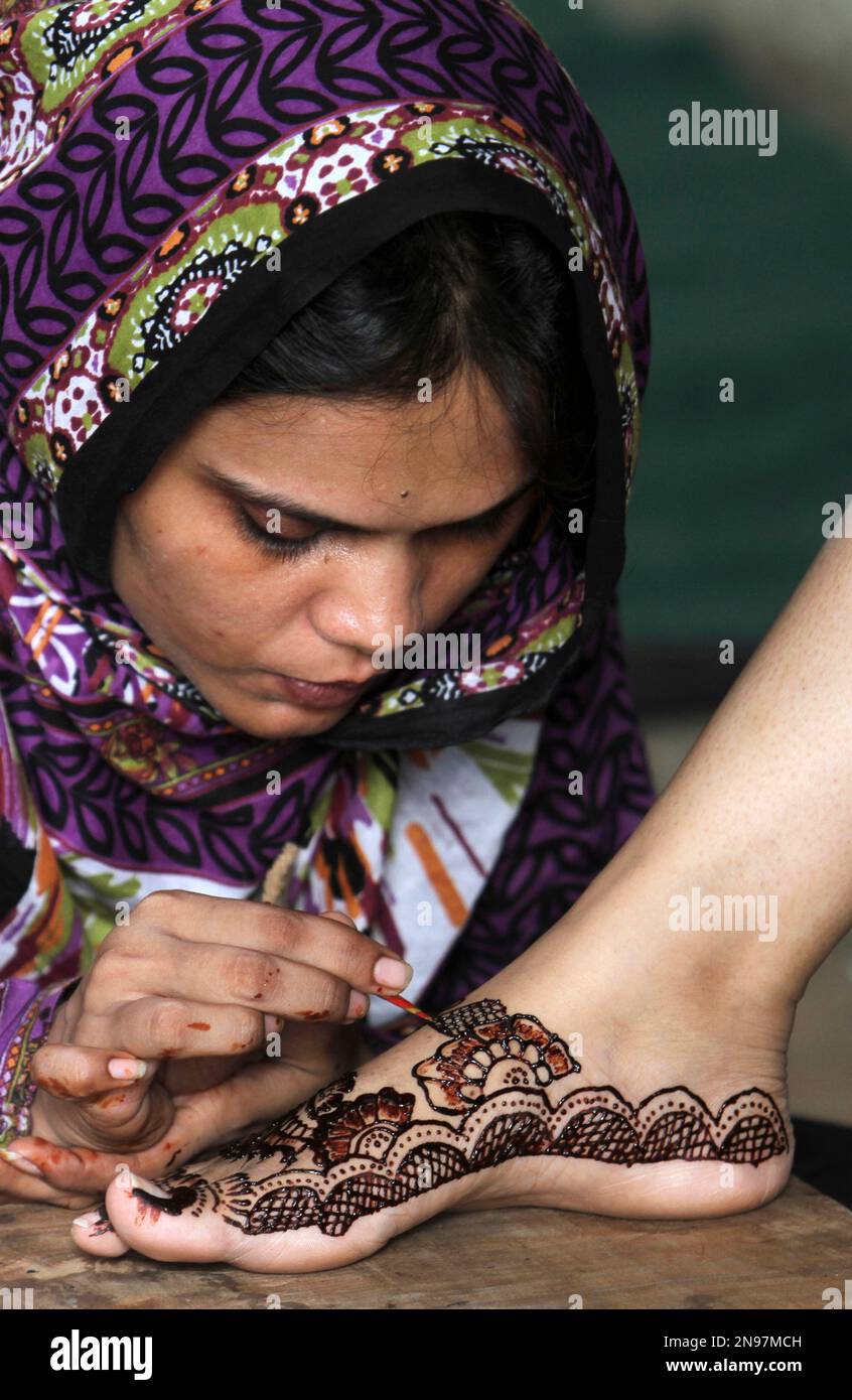 A Pakistani woman paints a customer's feet with henna in preparation ...