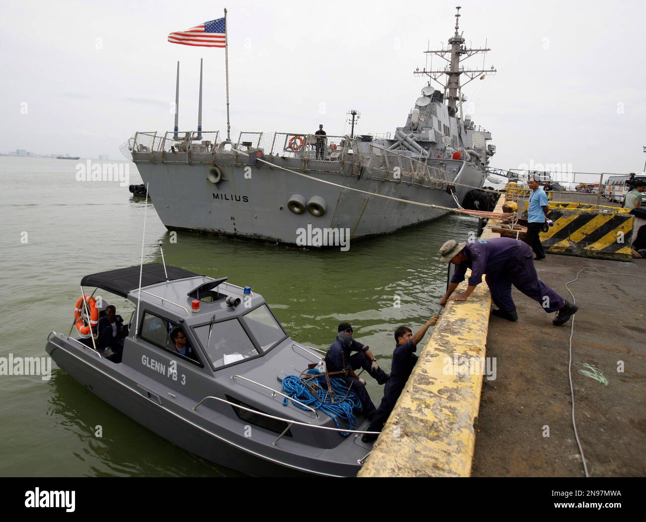 Filipino workers on a boat come to the pier behind the USS Milius (DDG ...