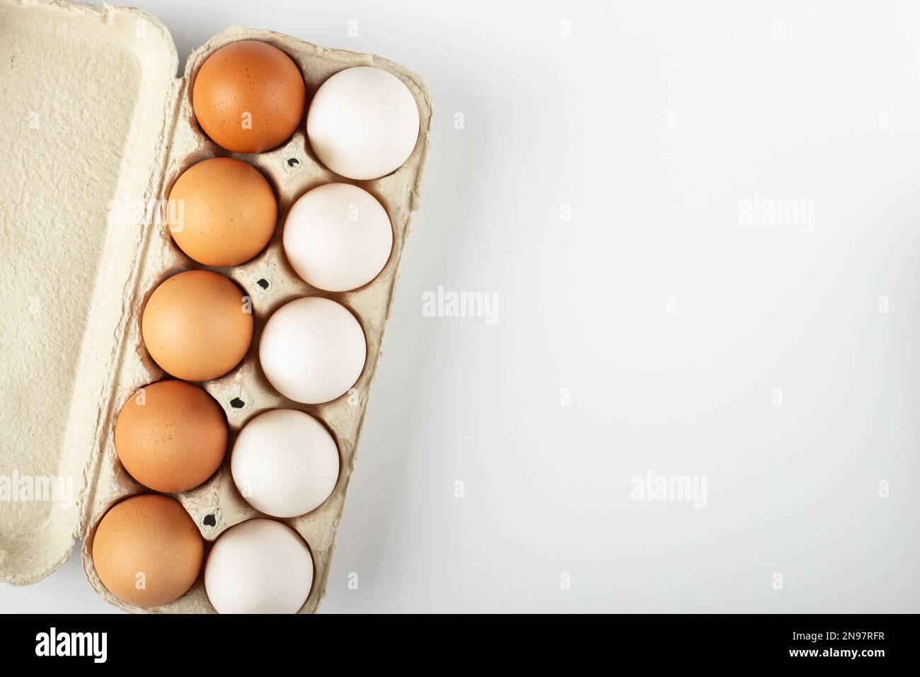 Raw chicken eggs in an egg tray on a white background. Space for text ...