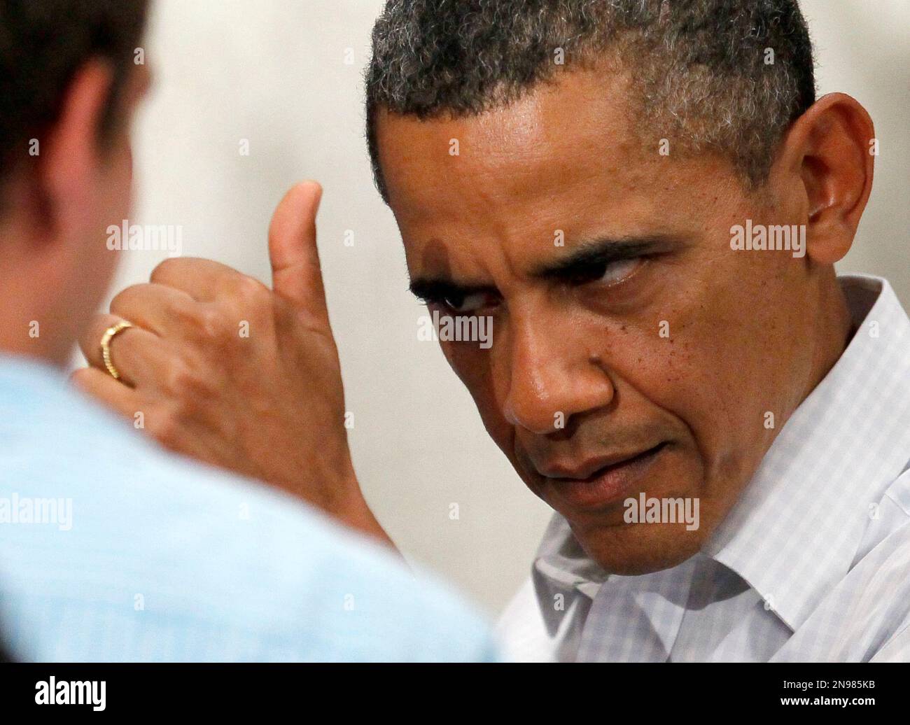 President Barack Obama shields the spotlight from his eyes as he works ...