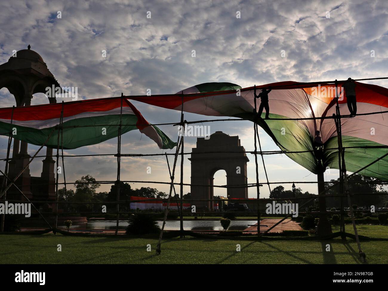 Indian workers hang a large Indian flag used to shield dignitaries at ...