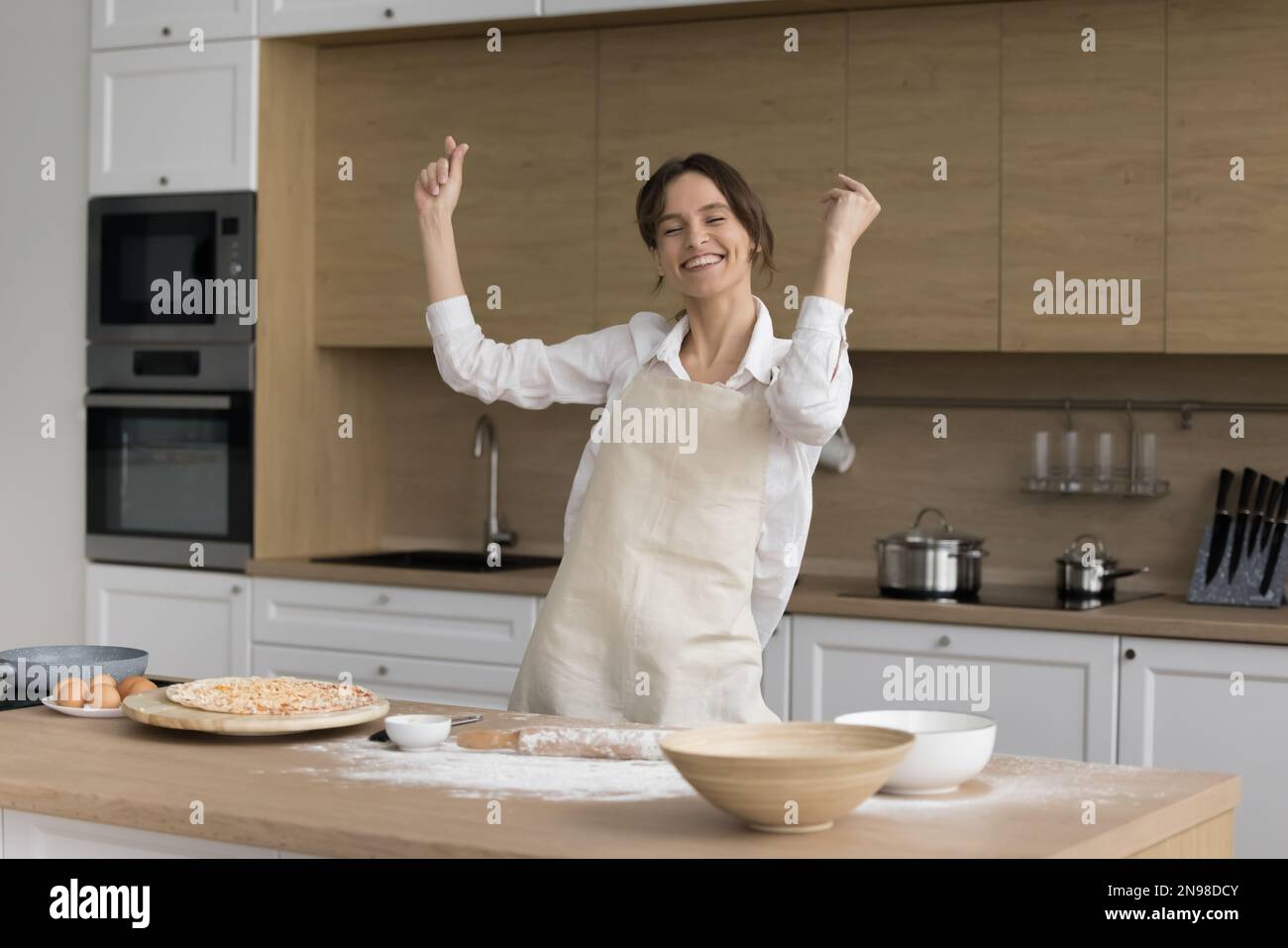 Happy active inspired baker girl in apron dancing to music Stock Photo ...