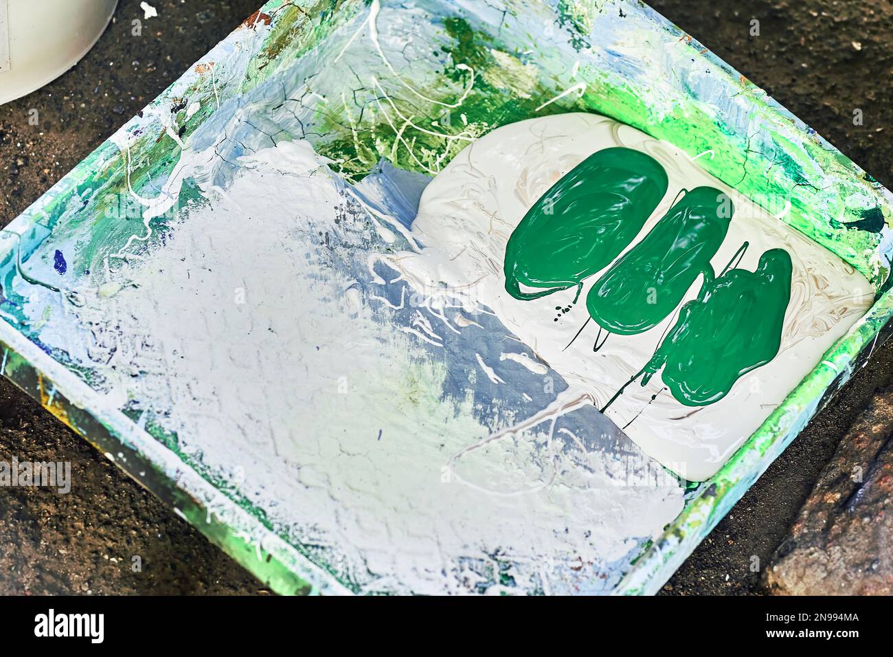 Painter craftsman artist tray at workplace with green and white paint ...