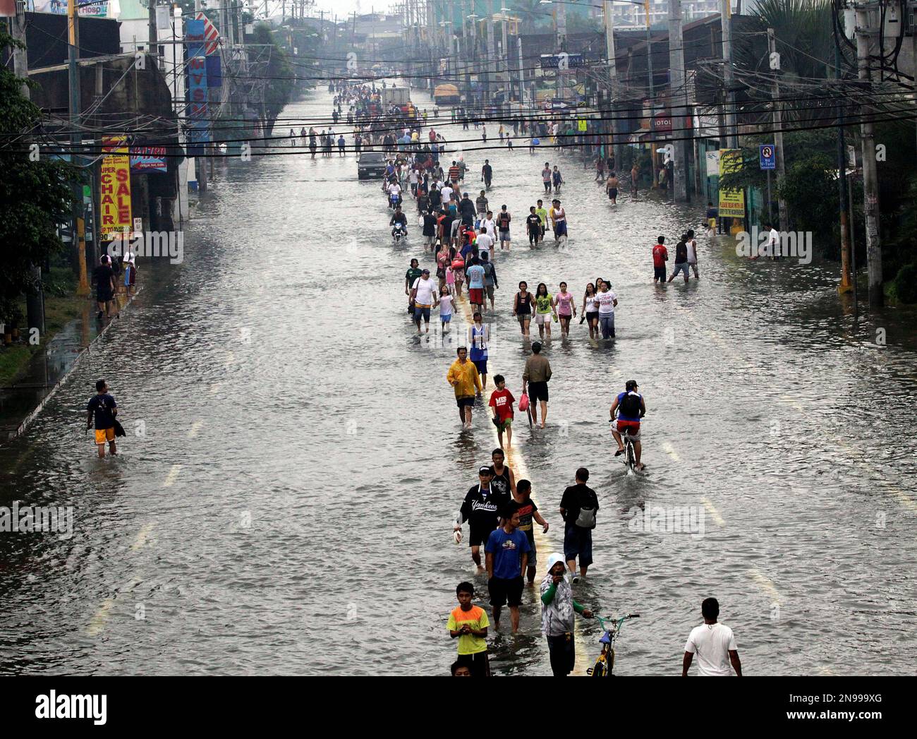 People walk on a flooded street Thursday, Aug. 9, 2012 in suburban ...