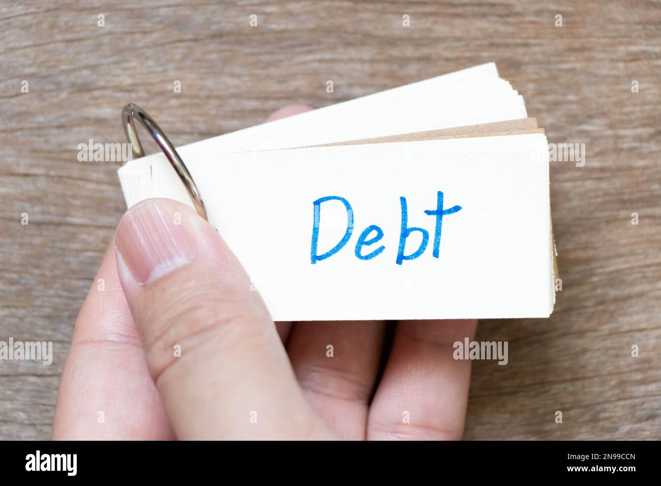 Hand hold flash card with handwriting in word debt on wood background ...