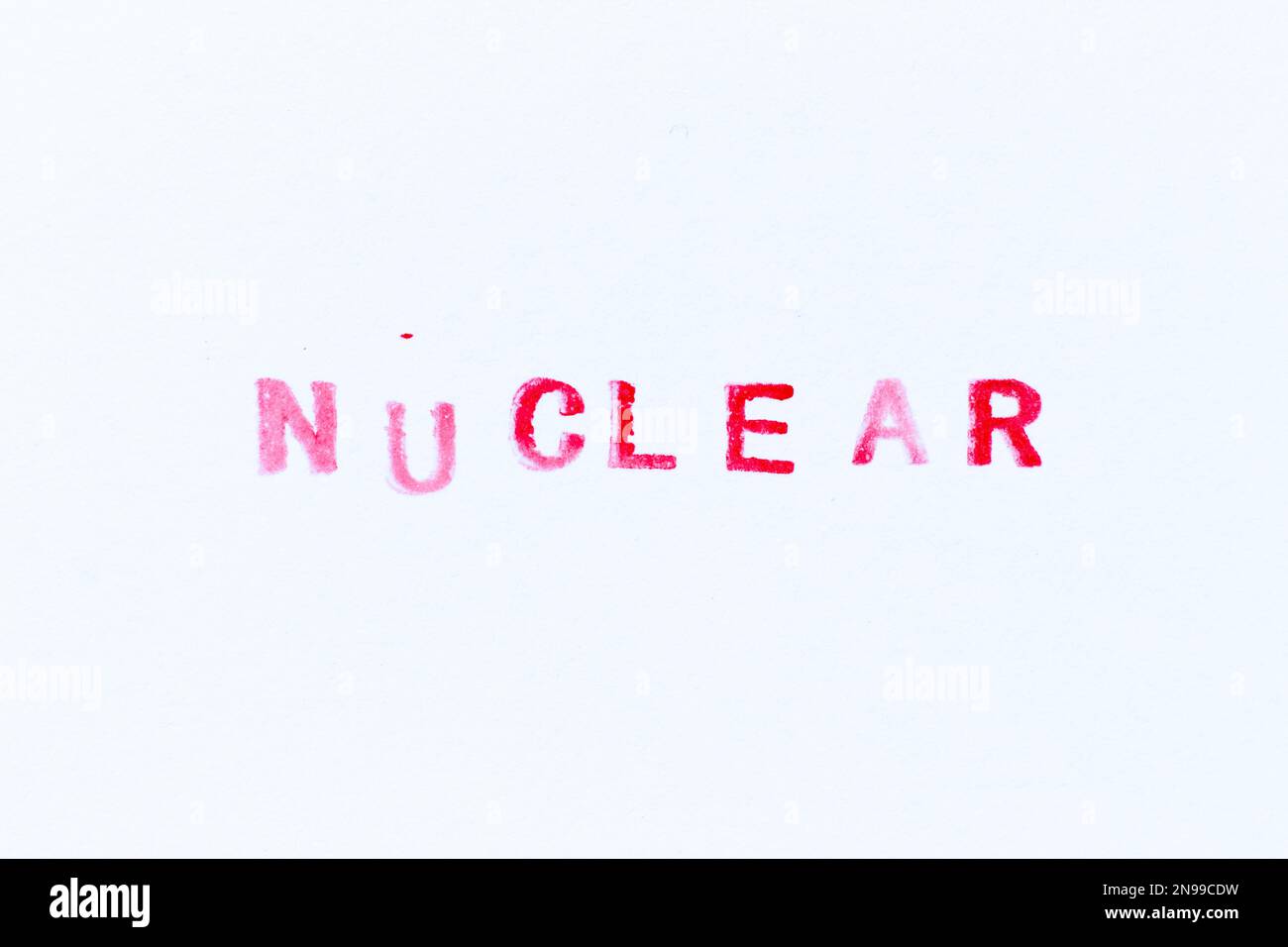 Red color ink rubber stamp in word nuclear on white paper background ...
