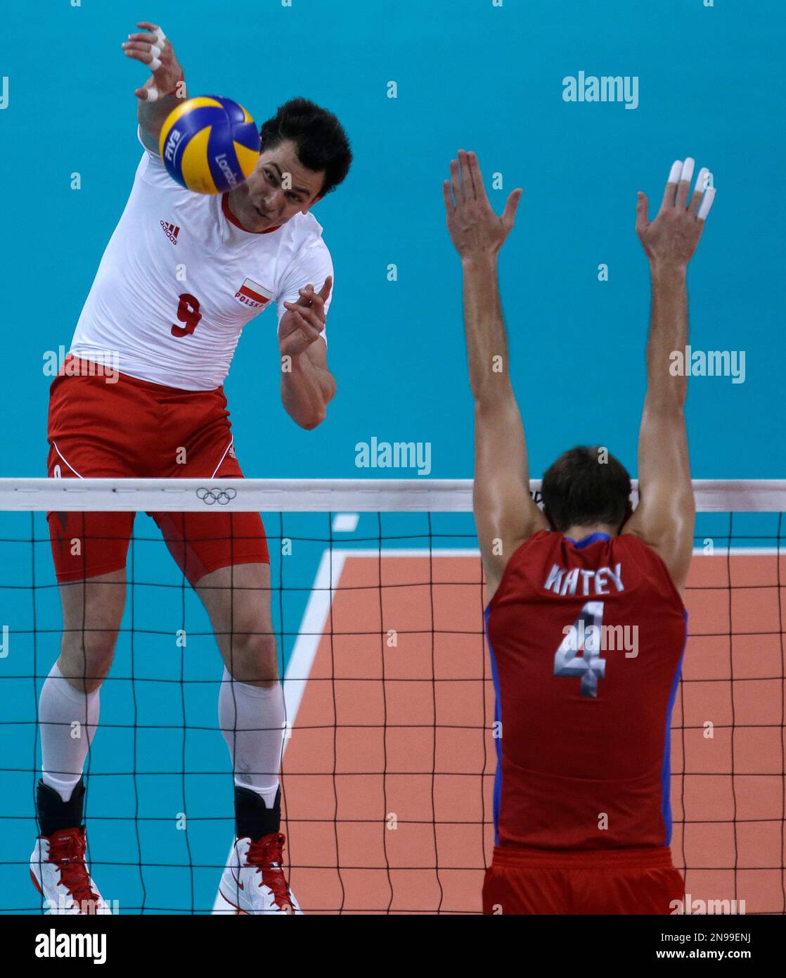 Poland's Zbigniew Bartman, left, spikes the ball over Russia's Taras ...