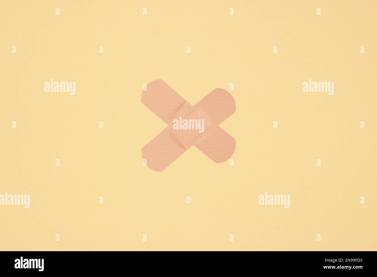 two strips of adhesive plaster tape in cross shape on skin colored ...