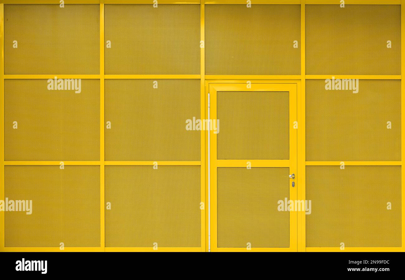 modern yellow building exterior with metallic facade and closed door ...