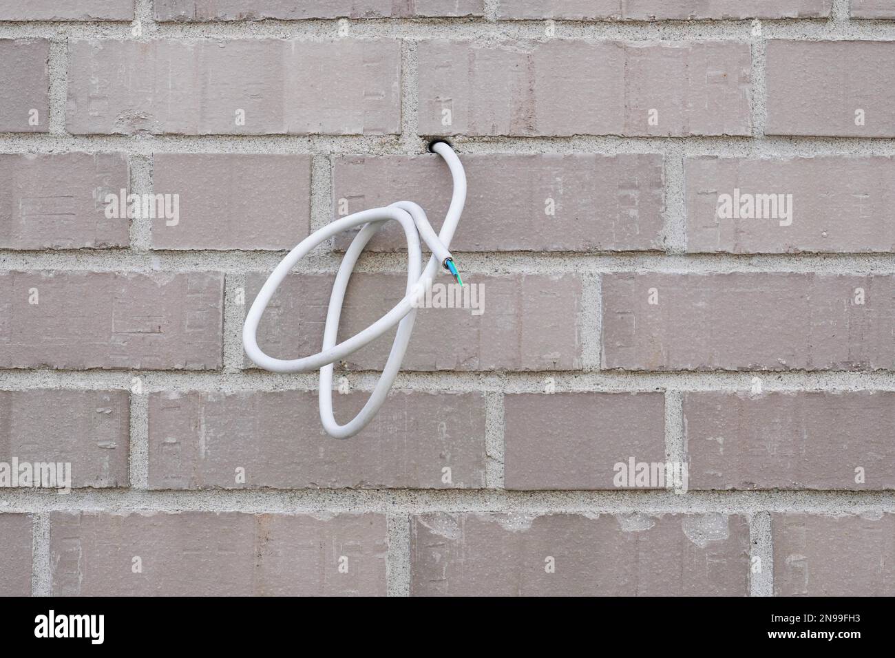 electrical wire or power cable hanging from exterior brick wall Stock ...