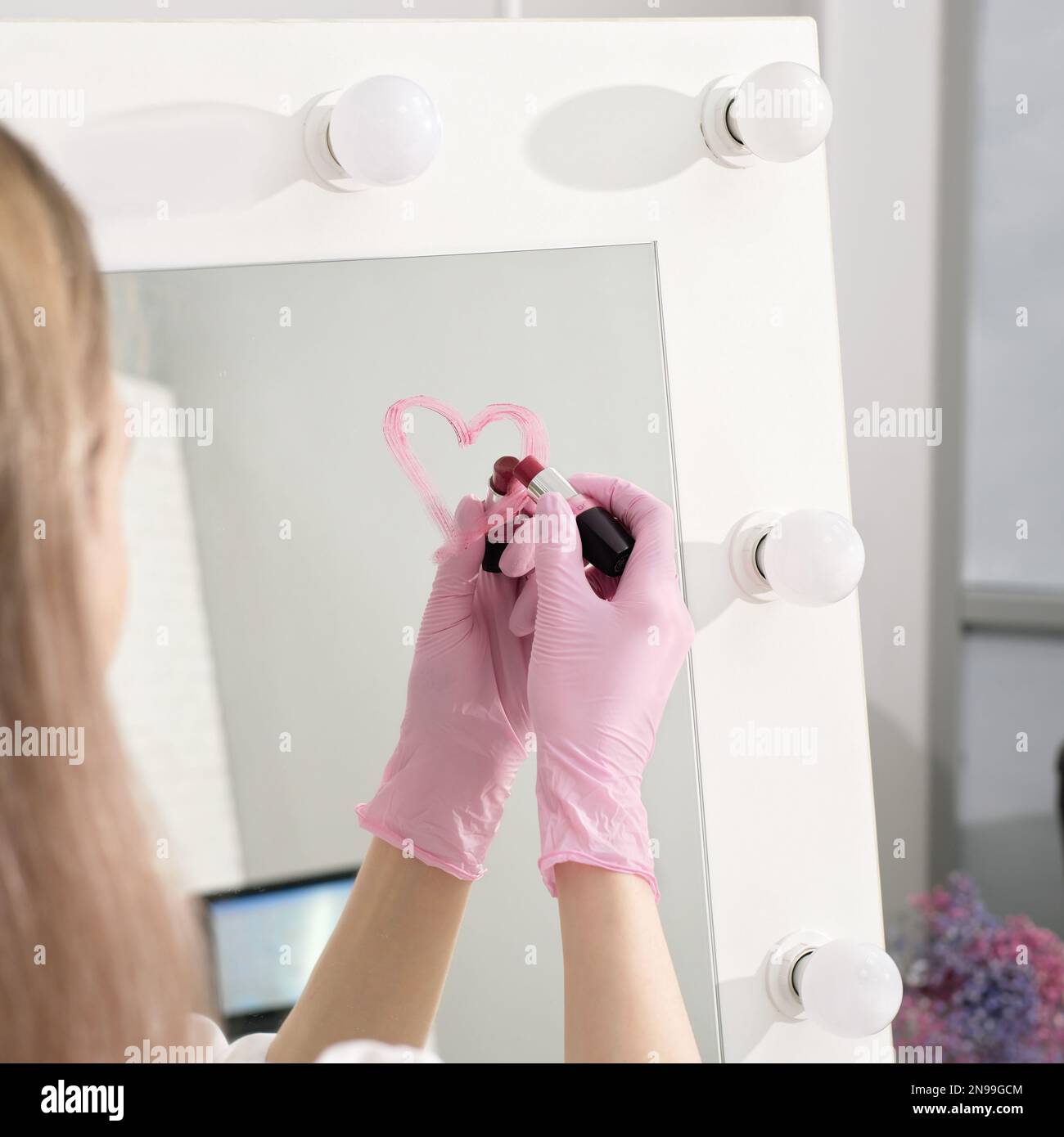 woman wearing medical protective gloves drawing a heart with lipstick ...