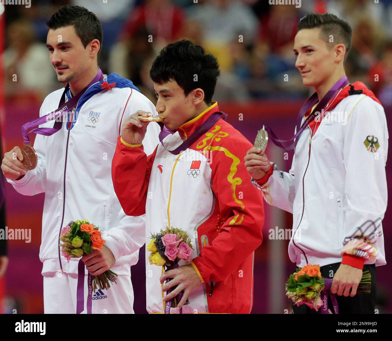 Chinese gymnast Feng Zhe, center, kisses his gold medal, as Germany's ...