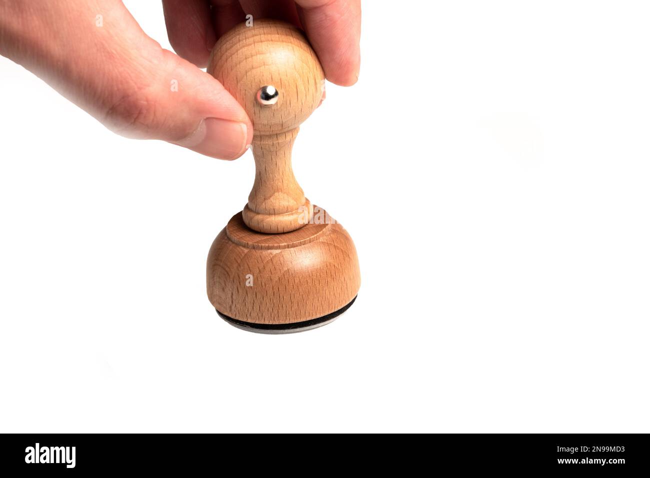 close-up of hand holding round wooden rubber stamp against white ...