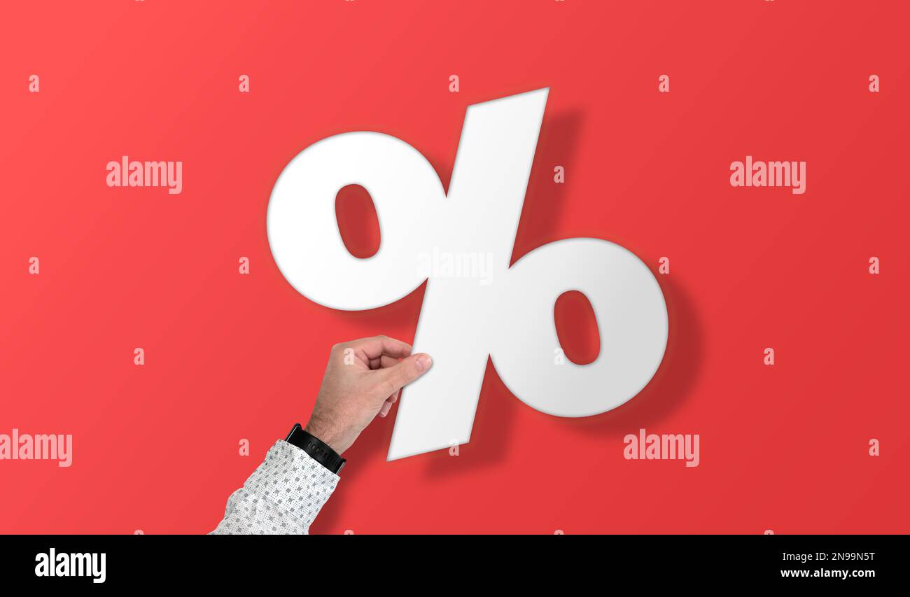 hand holding big percent sign against red background, discount and sale ...