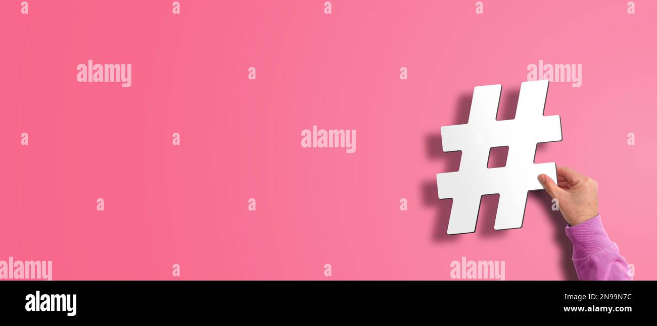 hand holding hash symbol, hashtag against pink background, social media ...