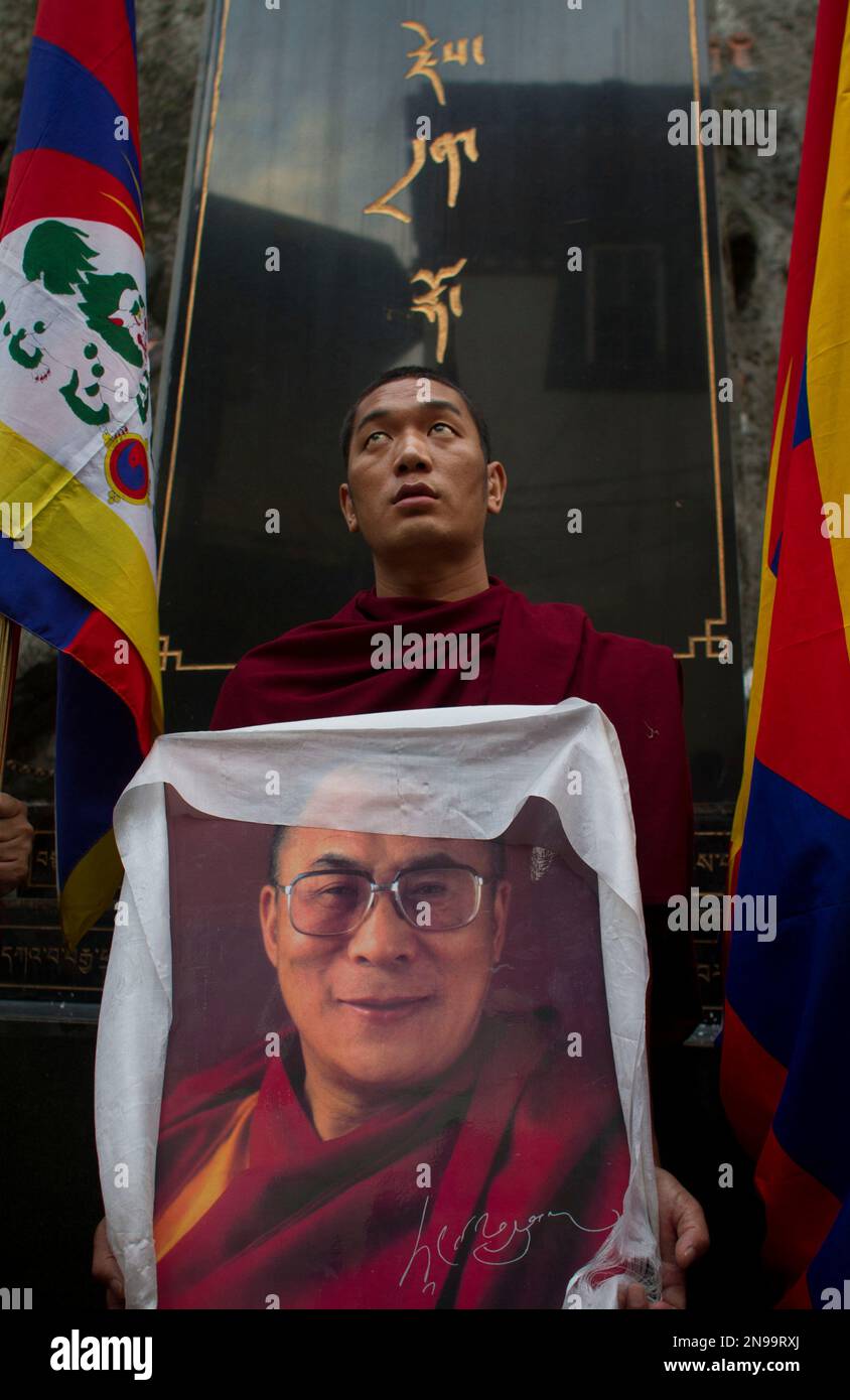 An exile Tibetan Buddhist monk holds a portrait of the Tibetan ...