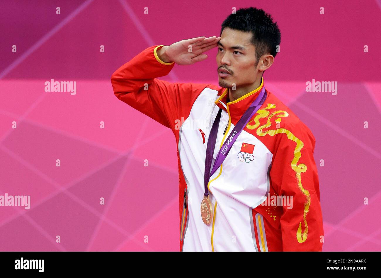 China's Lin Dan salutes his country's flag while listening the national ...