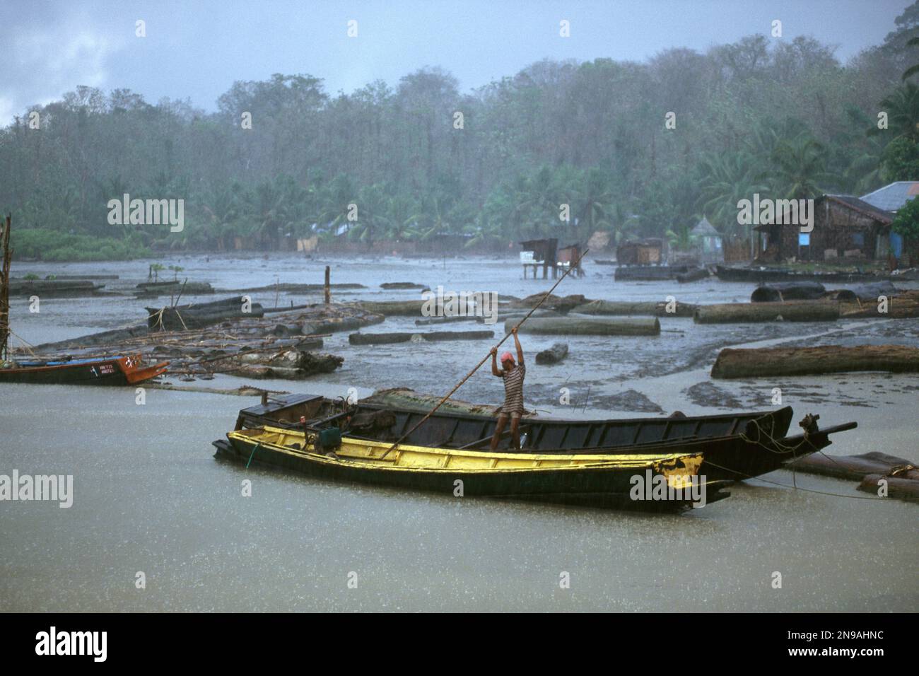 A boatmen tries to remove his boat as the rain pours, Andaman and ...