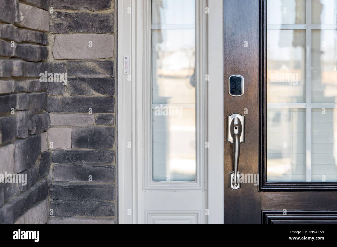 A Close-up of a wooden door with a brass doorknob, window and side ...