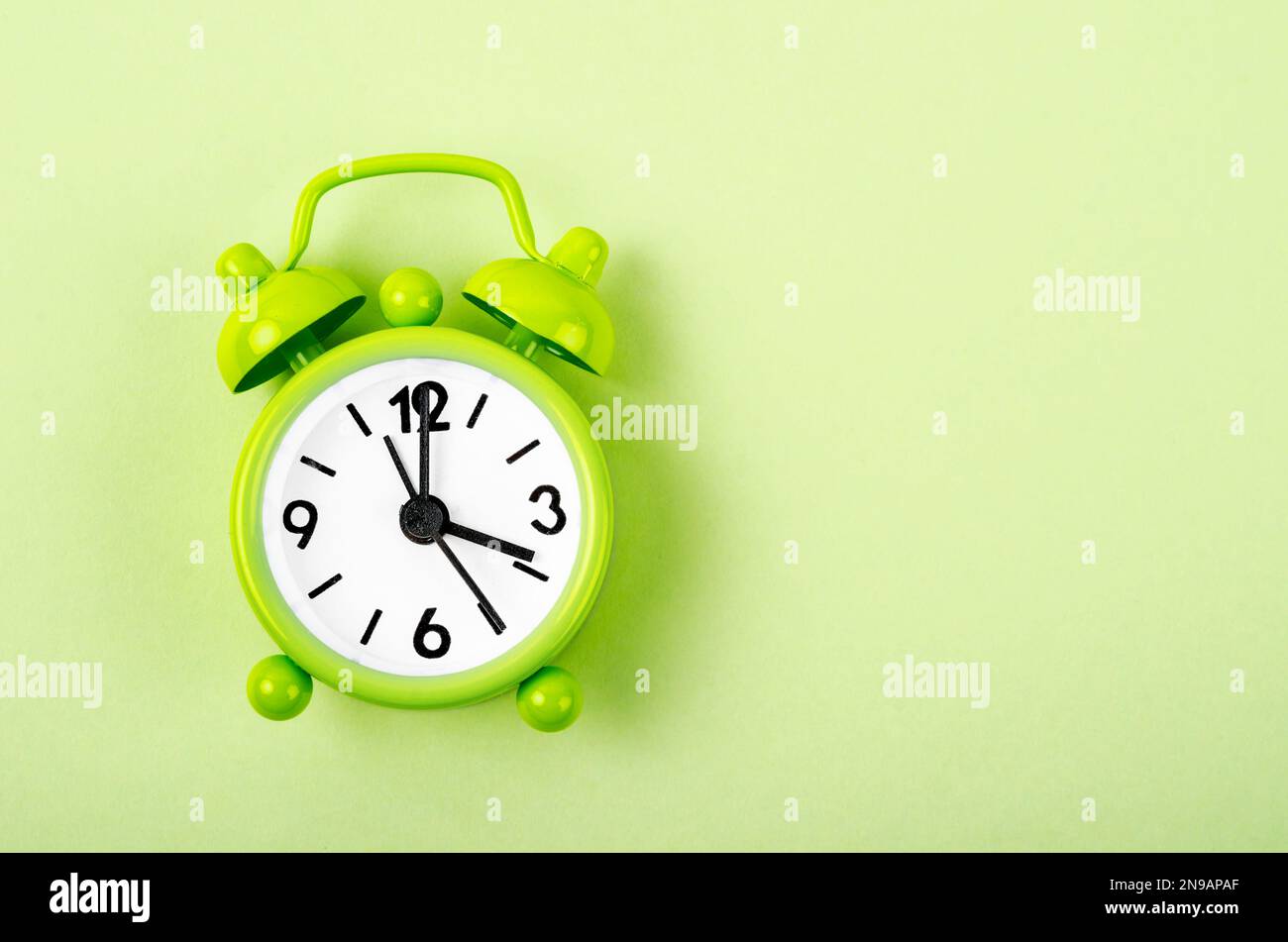 Green alarm clock on green colour background Stock Photo - Alamy