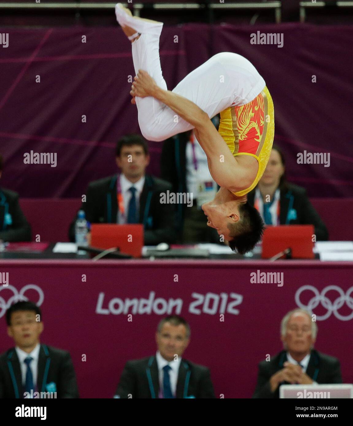 Judges watch the trampoline performance of gold medallist Dong Dong of ...