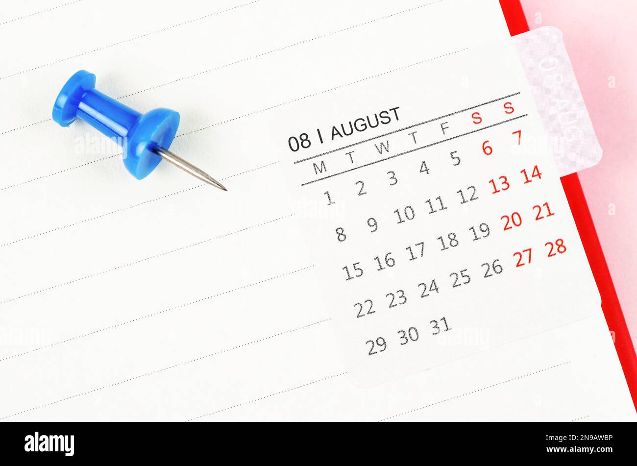 Mini August calendar on a white note book with push pin on pink colour ...