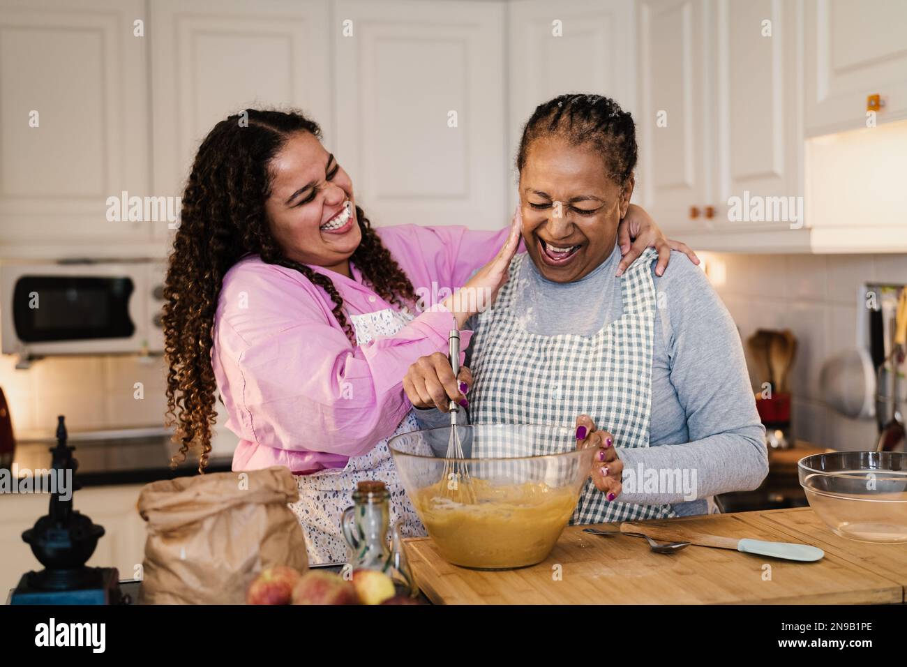 Happy African mother and daughter having fun preparing a homemade ...