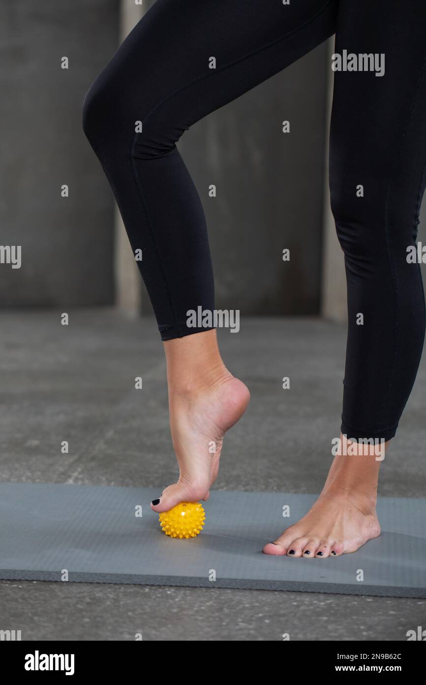 A woman does self-massage of the feet with a prickly ball, relaxation ...