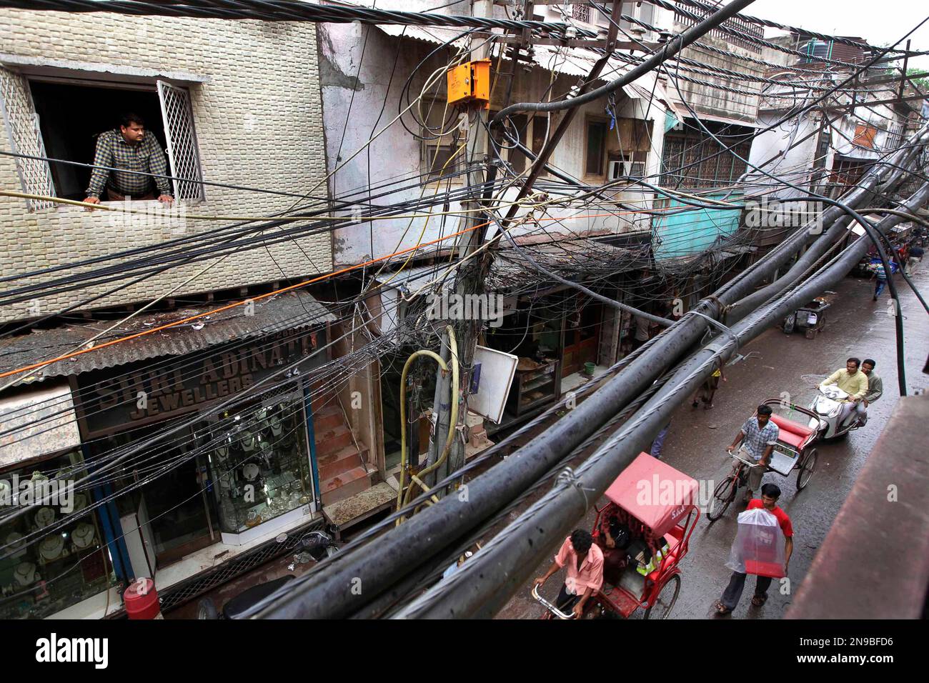 An Indian man looks at a maze of electric cables from a window of his ...