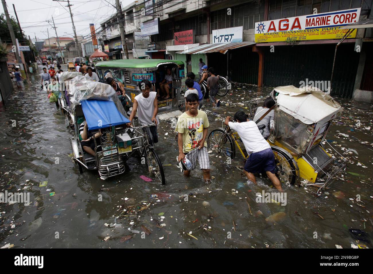 Filipinos wade along garbage-laden floodwaters at Navotas city, north ...