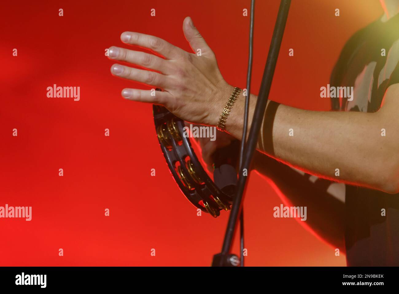 Musician playing on tambourine on rock concert stage. Hands of adult ...