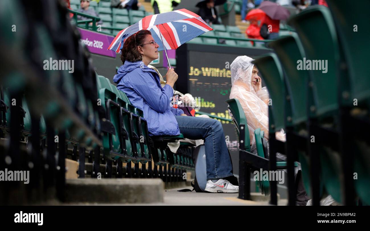 Sue Healey watches the clouds from under her umbrella during a rain ...
