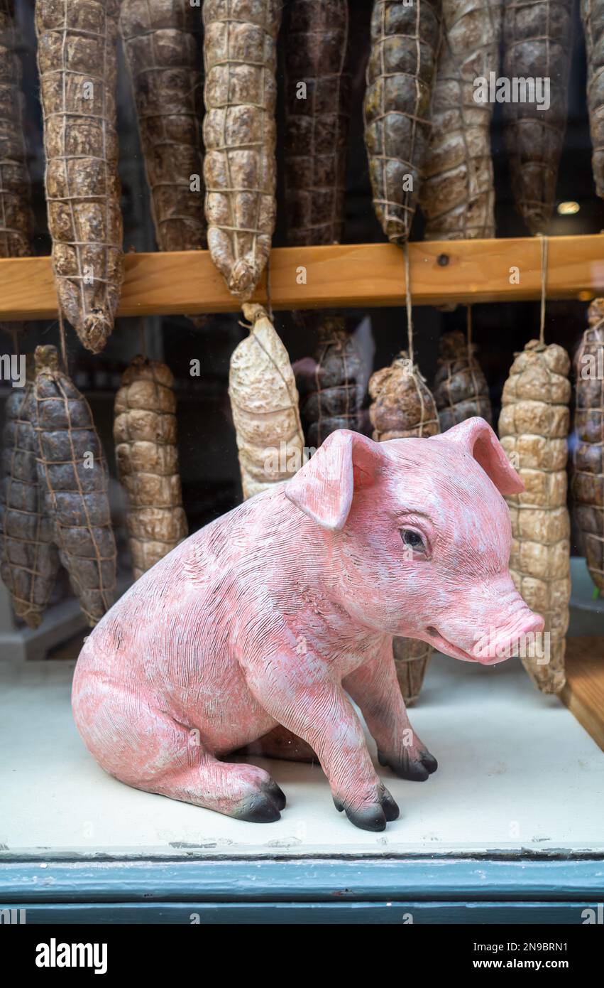 A figure of a pig in front of salamis in the window of a butcher shop ...