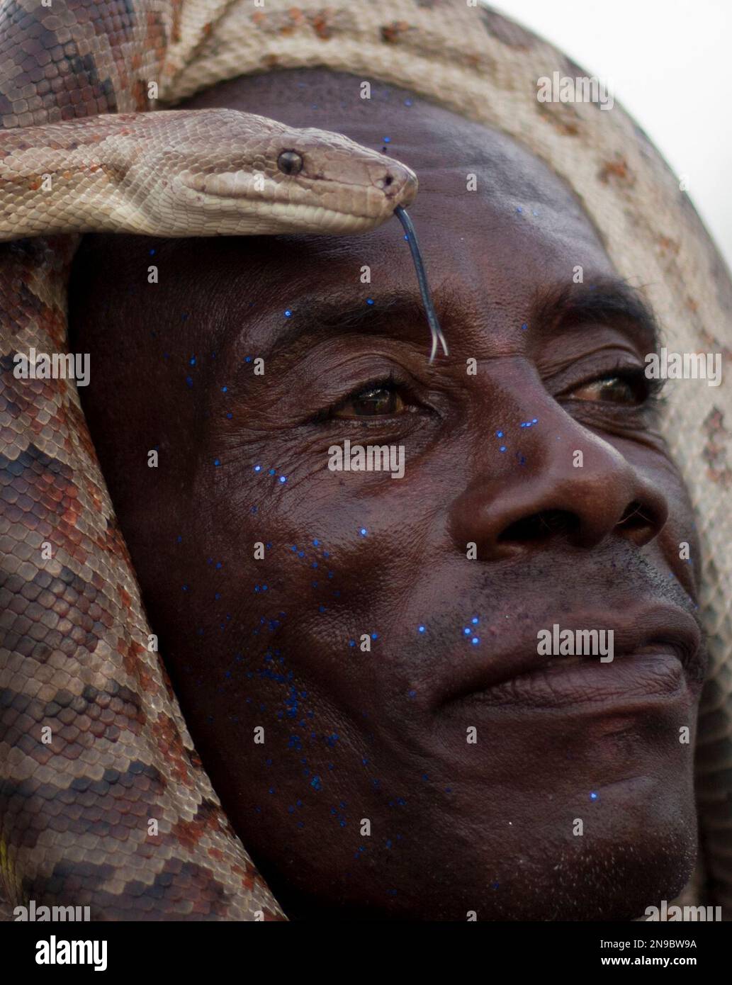A man carrying snakes around his head parades during carnival of ...