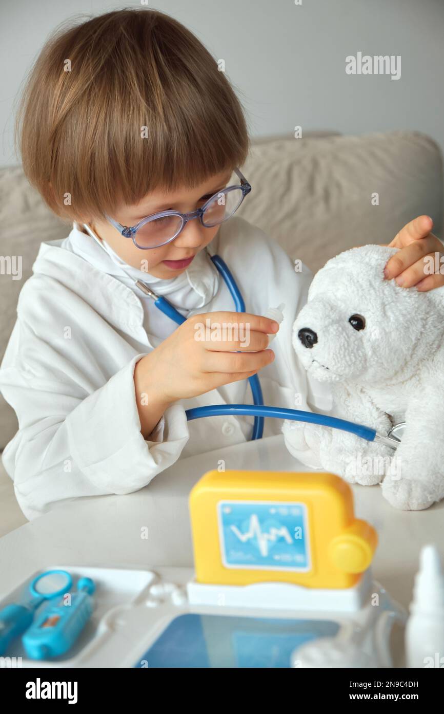 Little doctor in medical coat with stethoscope play eye treatment to ...