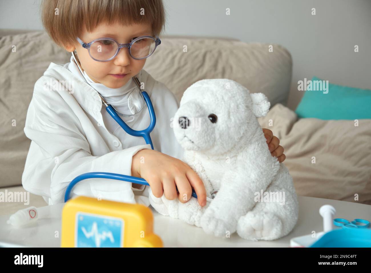 Little doctor in medical coat with stethoscope play an examination of ...