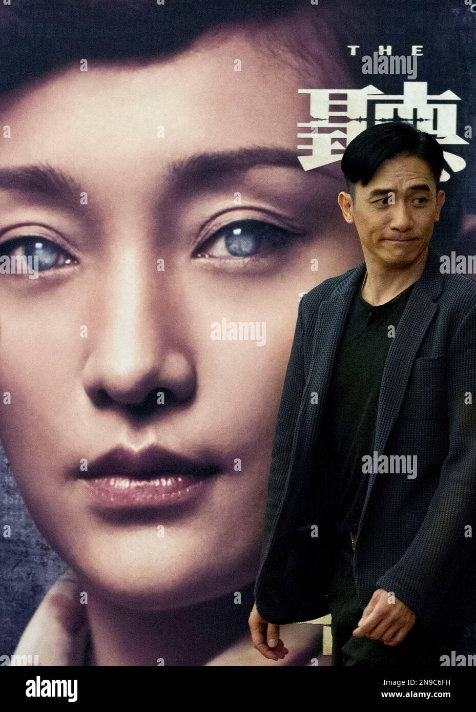 Hong Kong actor Tony Leung walks past a movie poster showing Chinese ...