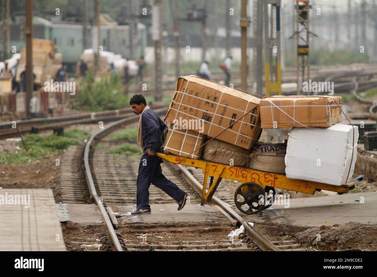 An Indian railway worker pulls a cart with freight across the tracks at ...