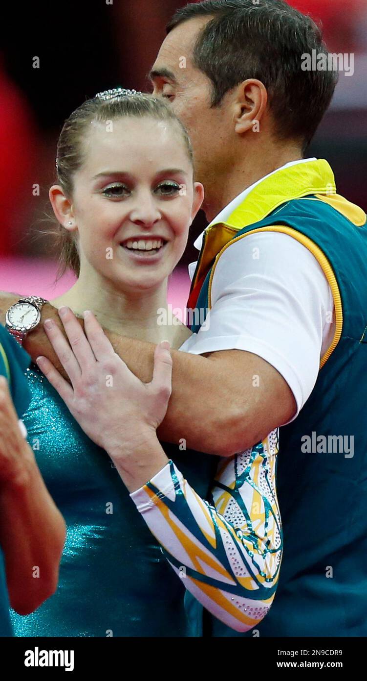Australian gymnast Lauren Mitchell is hugged by a team official during ...