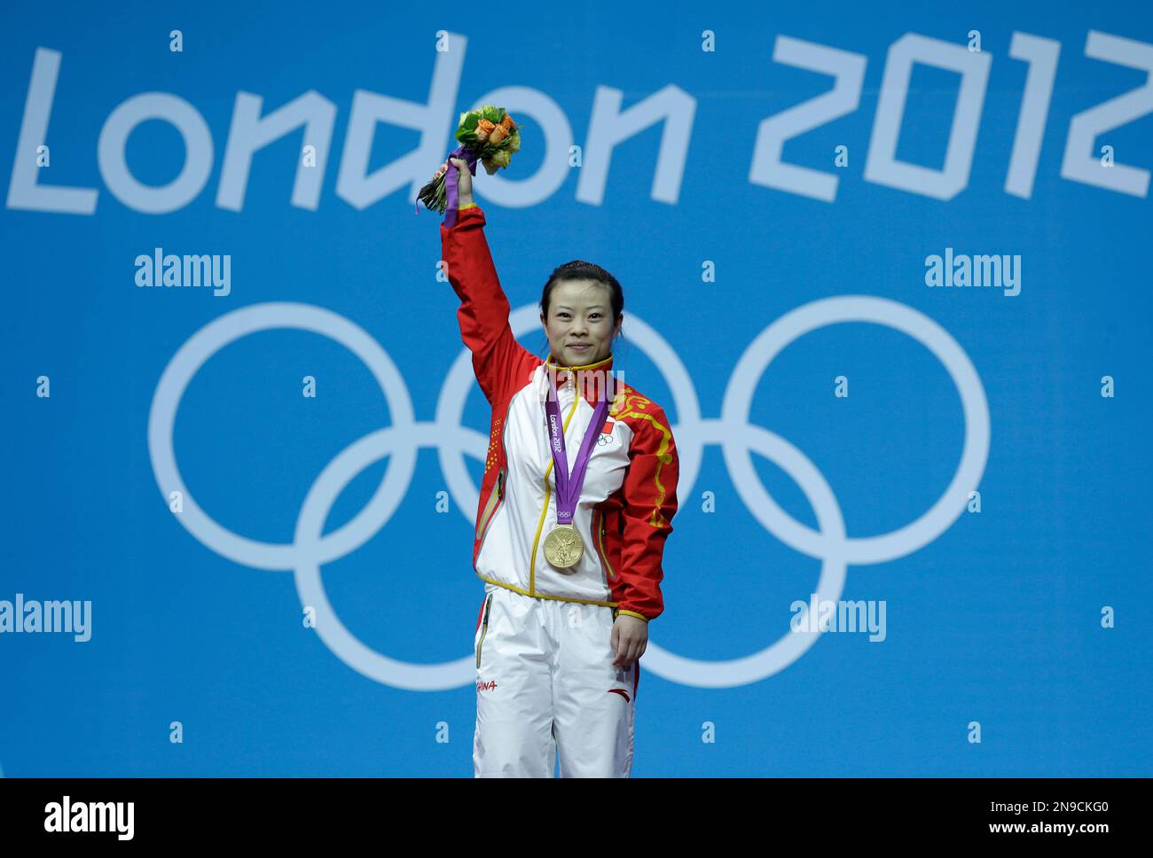 China's Wang Mingjuan holds up flowers during a medals ceremony after ...