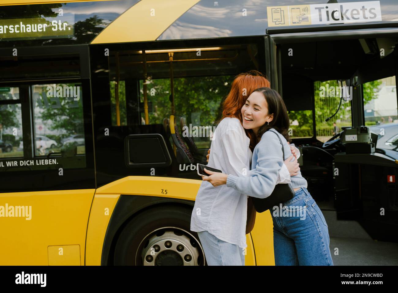 Young cute smiling asian girl hugging her beautiful redhead friend near ...