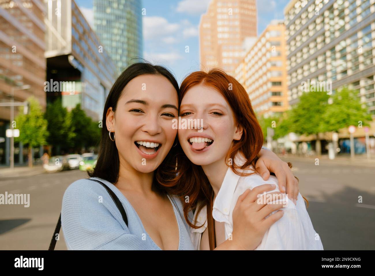 Two young beautiful smiling happy girls hugging each other and touching ...