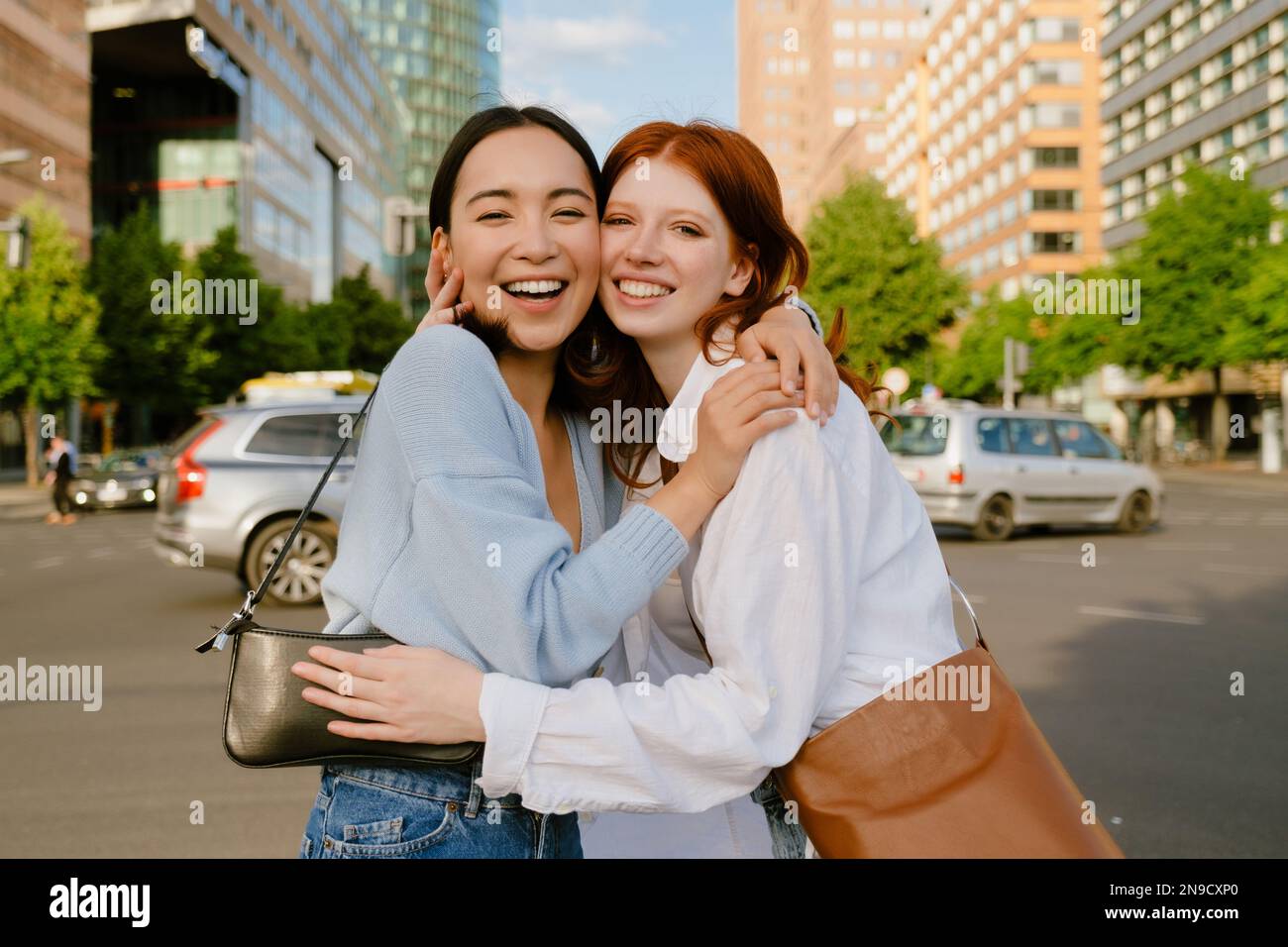 Two young beautiful smiling happy girls hugging each other and touching ...